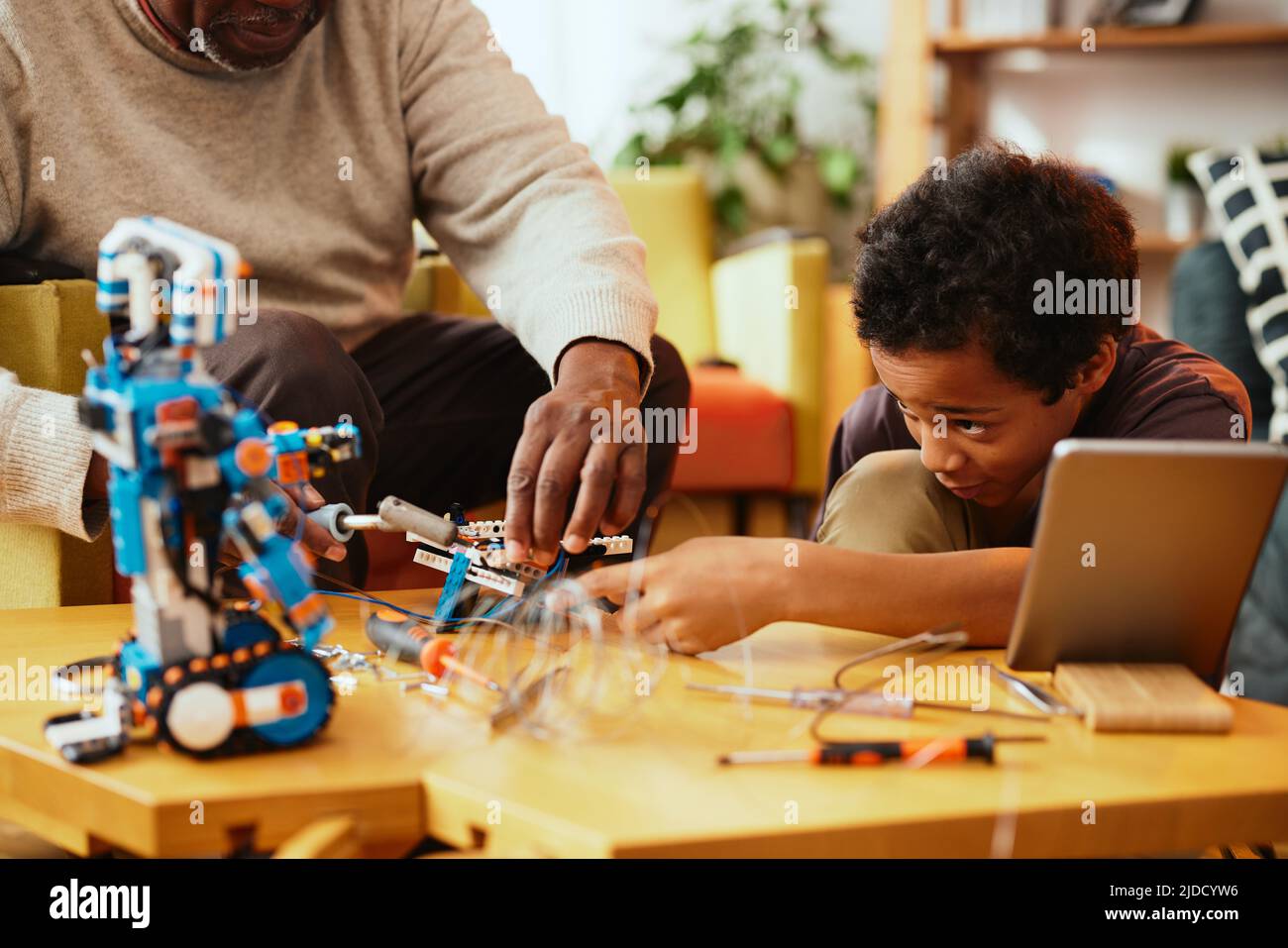 A grandfather showing his grandchild how to make a robot while sitting ...