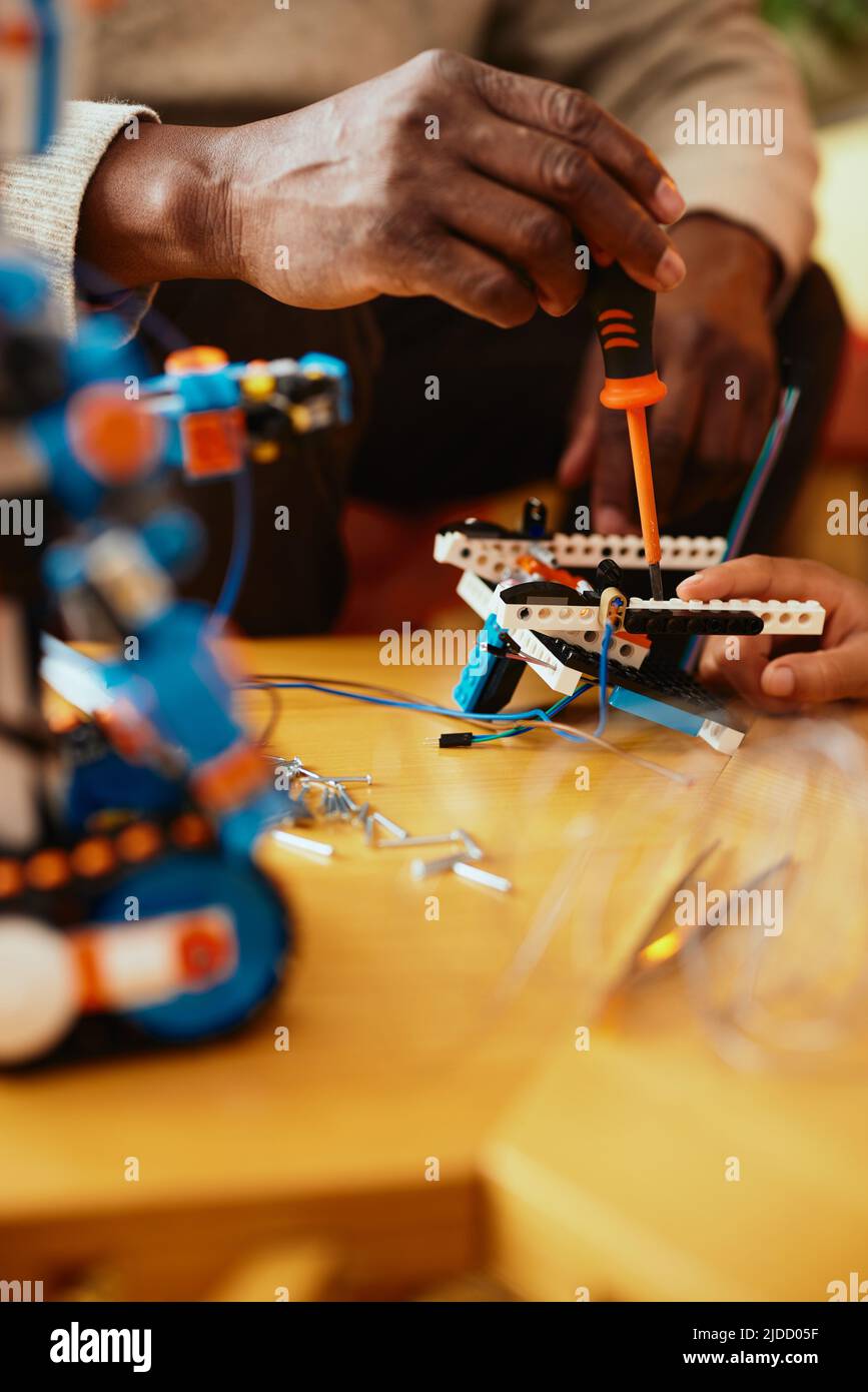 Close up of grandpa's hand helping his grandson to build a robot for ...