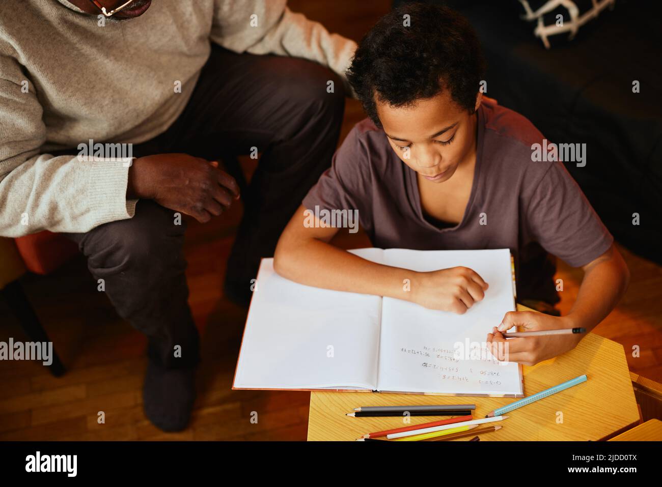Smart African boy doing his math homework with a little help of his ...