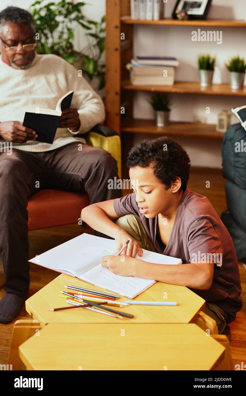 An African-American grandfather sitting in his chair and reading a book ...