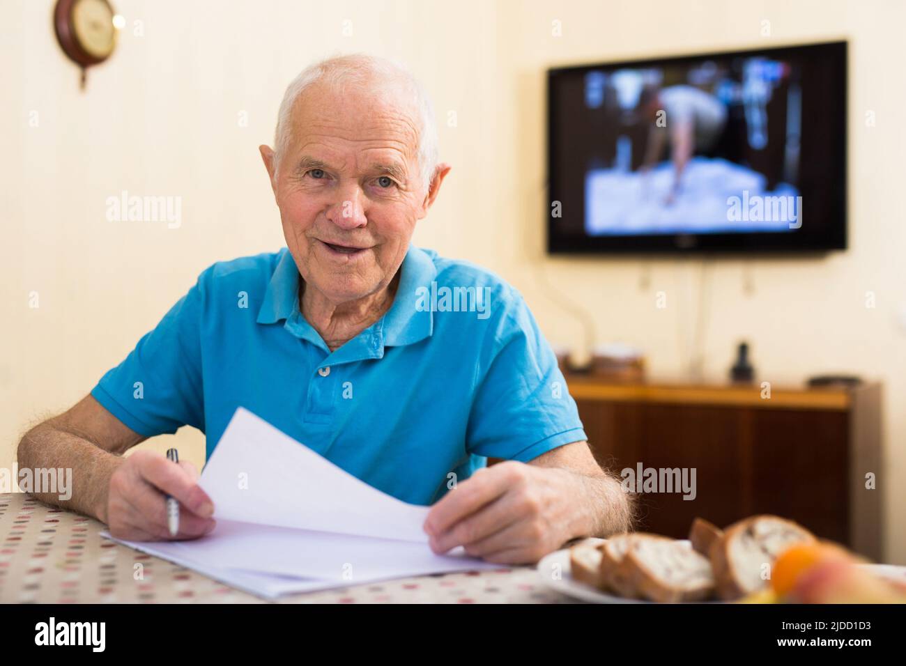 Cheerful elderly man sitting at home table with papers Stock Photo - Alamy