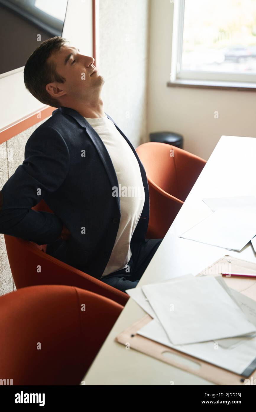 Desk worker stretching his back during paperwork Stock Photo - Alamy
