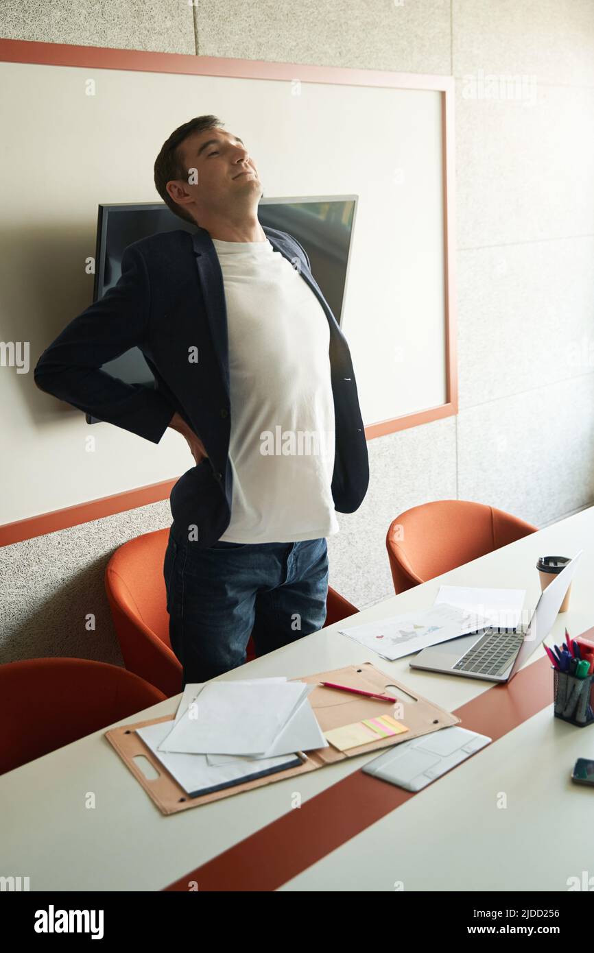 Male getting up and stretching to straighten his back Stock Photo - Alamy