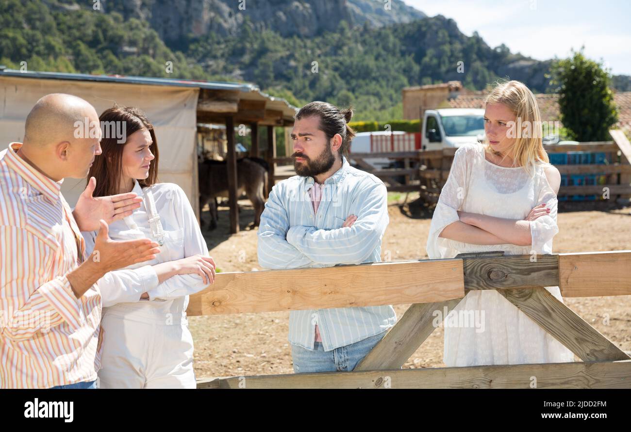 Displeased couples talking through wooden fence Stock Photo - Alamy