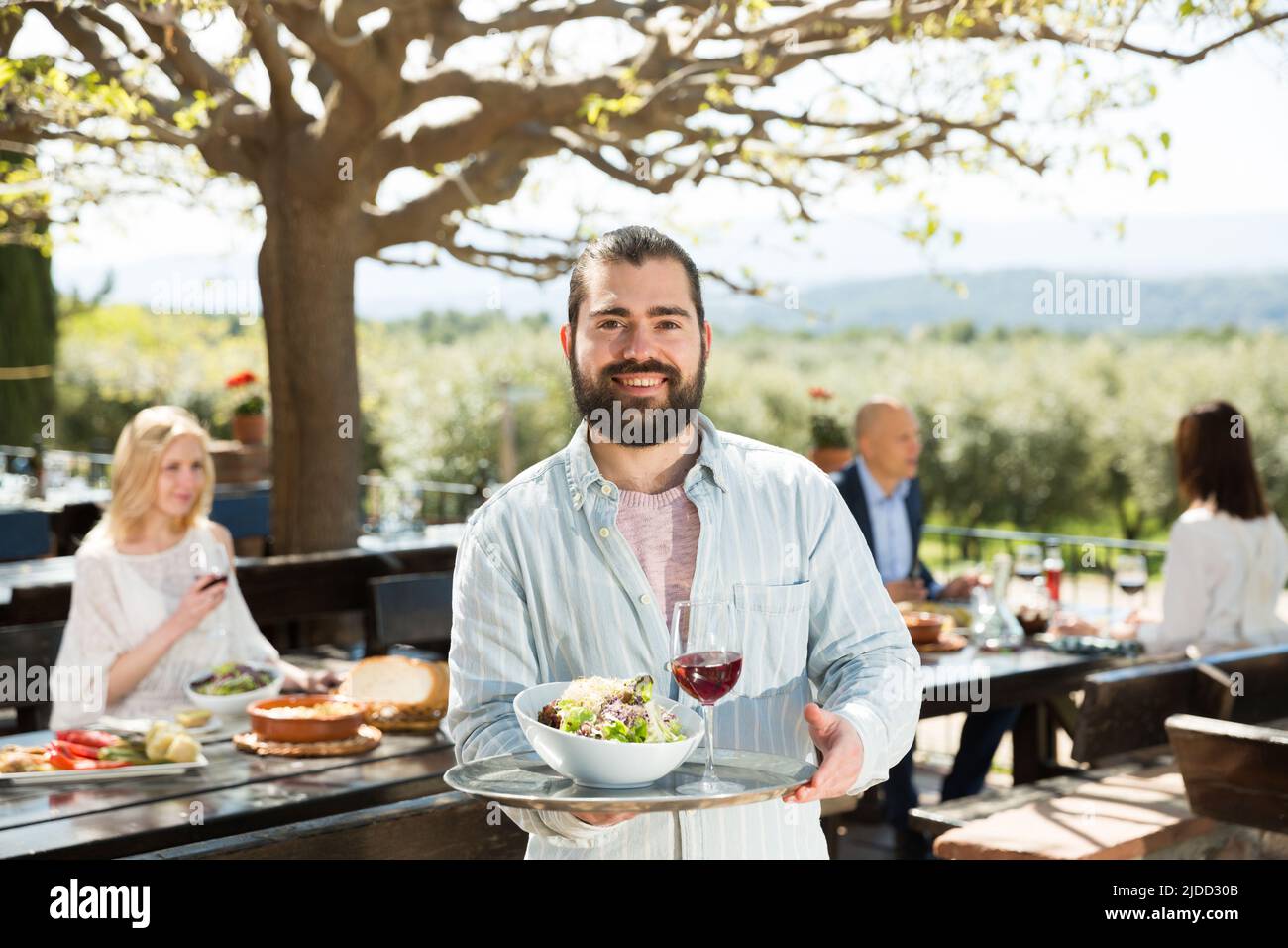 Bearded waiter inviting on outdoor terrace Stock Photo - Alamy