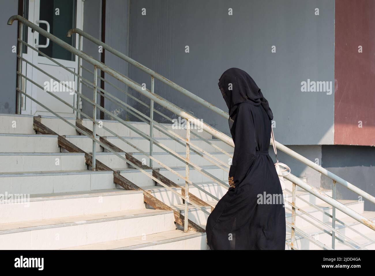 Tired Muslim woman climbs stairs into the house after work Stock Photo ...