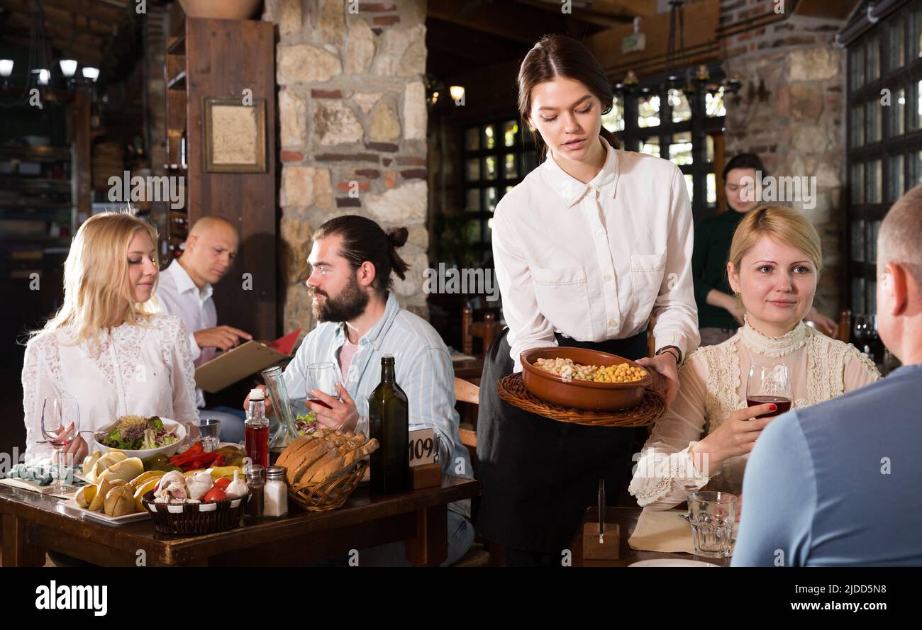 Female owner of rustic restaurant serving guests Stock Photo - Alamy