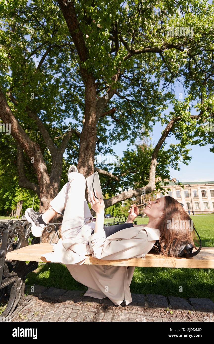 Lady is studying with book and notes on park bench Stock Photo - Alamy