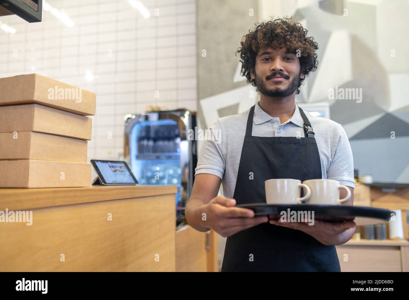 Man holding tray walking towards camera Stock Photo - Alamy