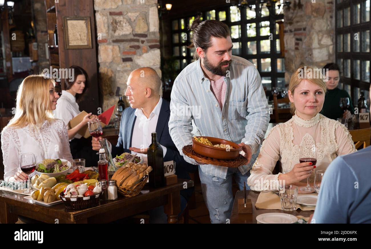 Waiter placing order in front of guests in country restaurant Stock ...