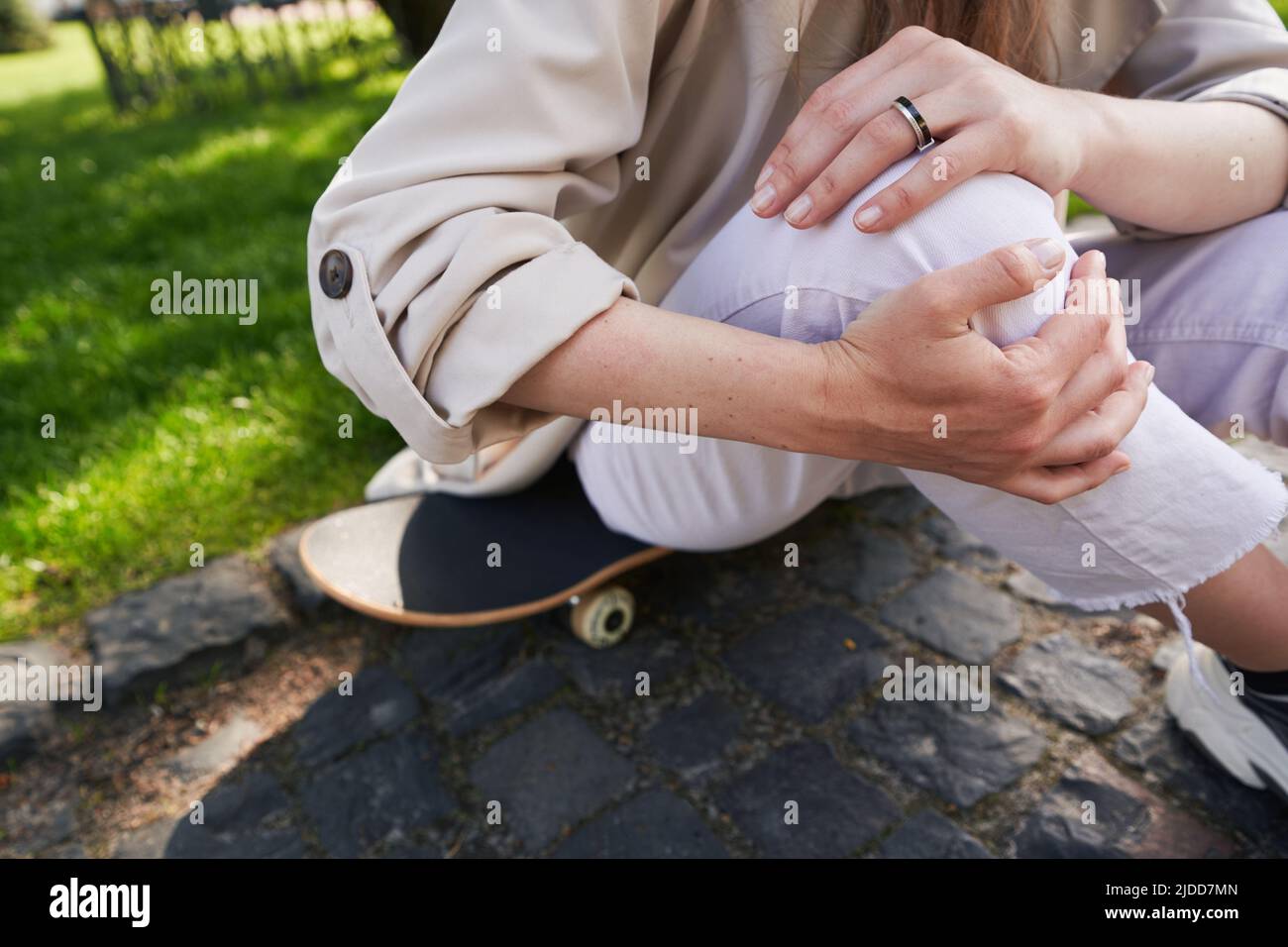 Lady is siting on skateboard holding her knee with hands Stock Photo ...