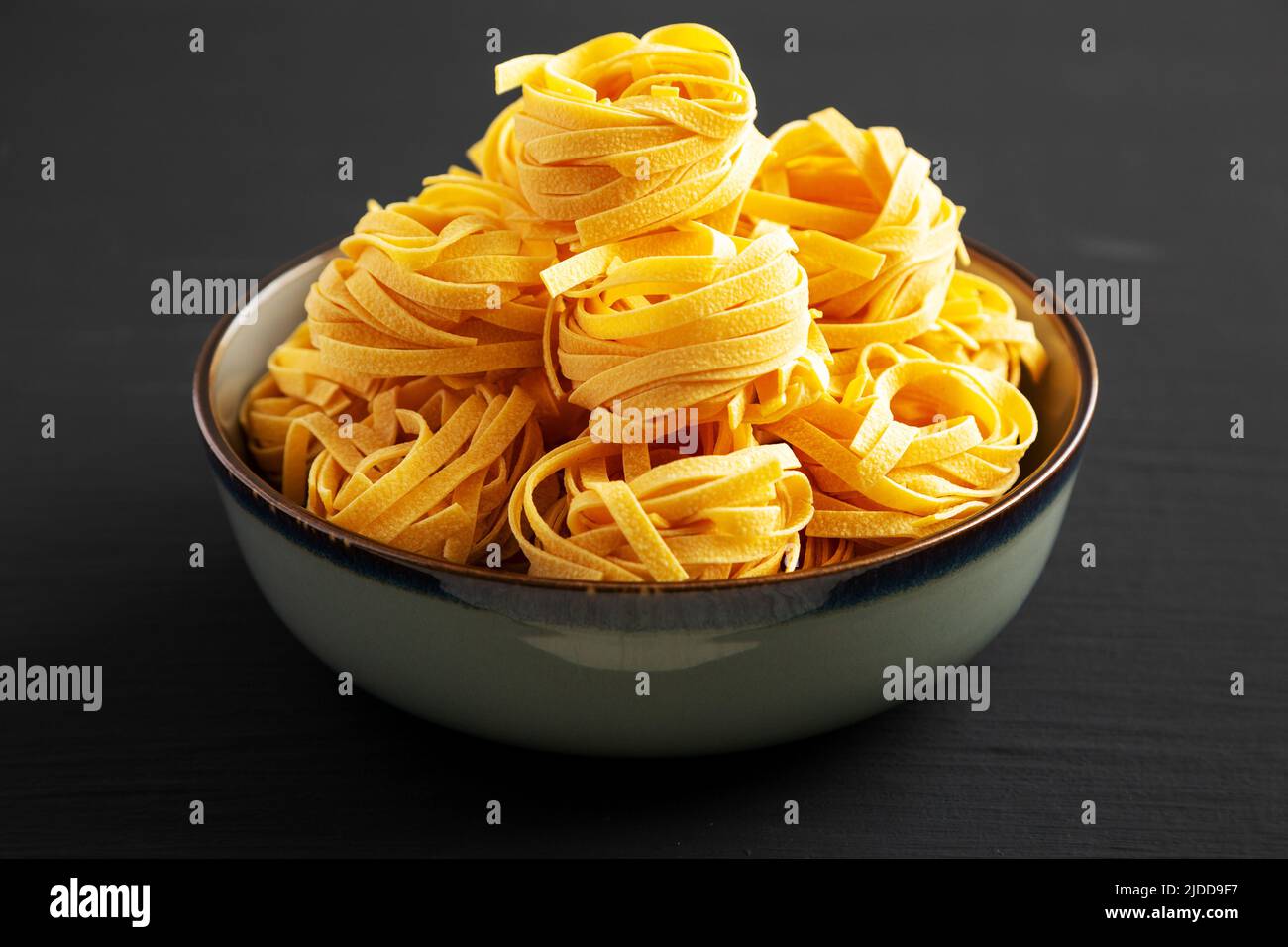Homemade Organic Dry Tagliatelle Pasta in a Bowl on a black background ...