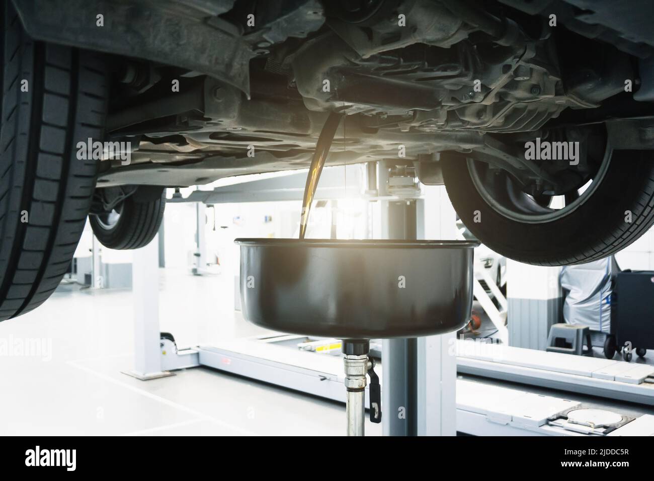 Engine oil change in car service. Auto is on hydraulic lift in garage ...