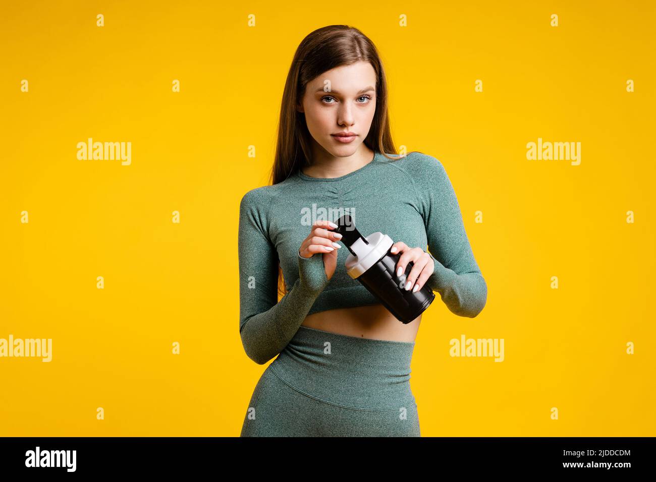 Beautiful sports girl holding a shaker on a yellow background Stock ...