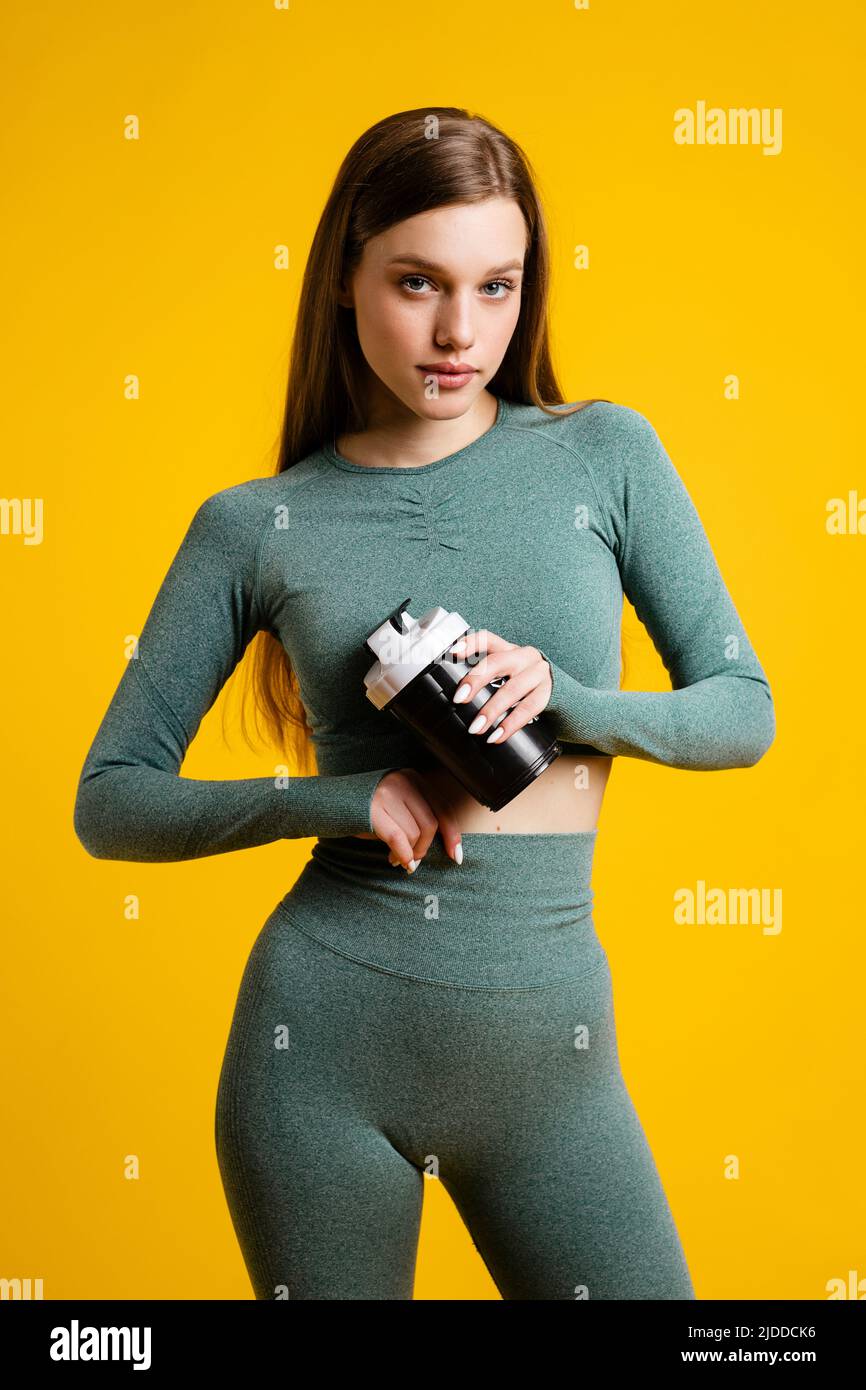 Beautiful sports girl holding a shaker on a yellow background Stock ...