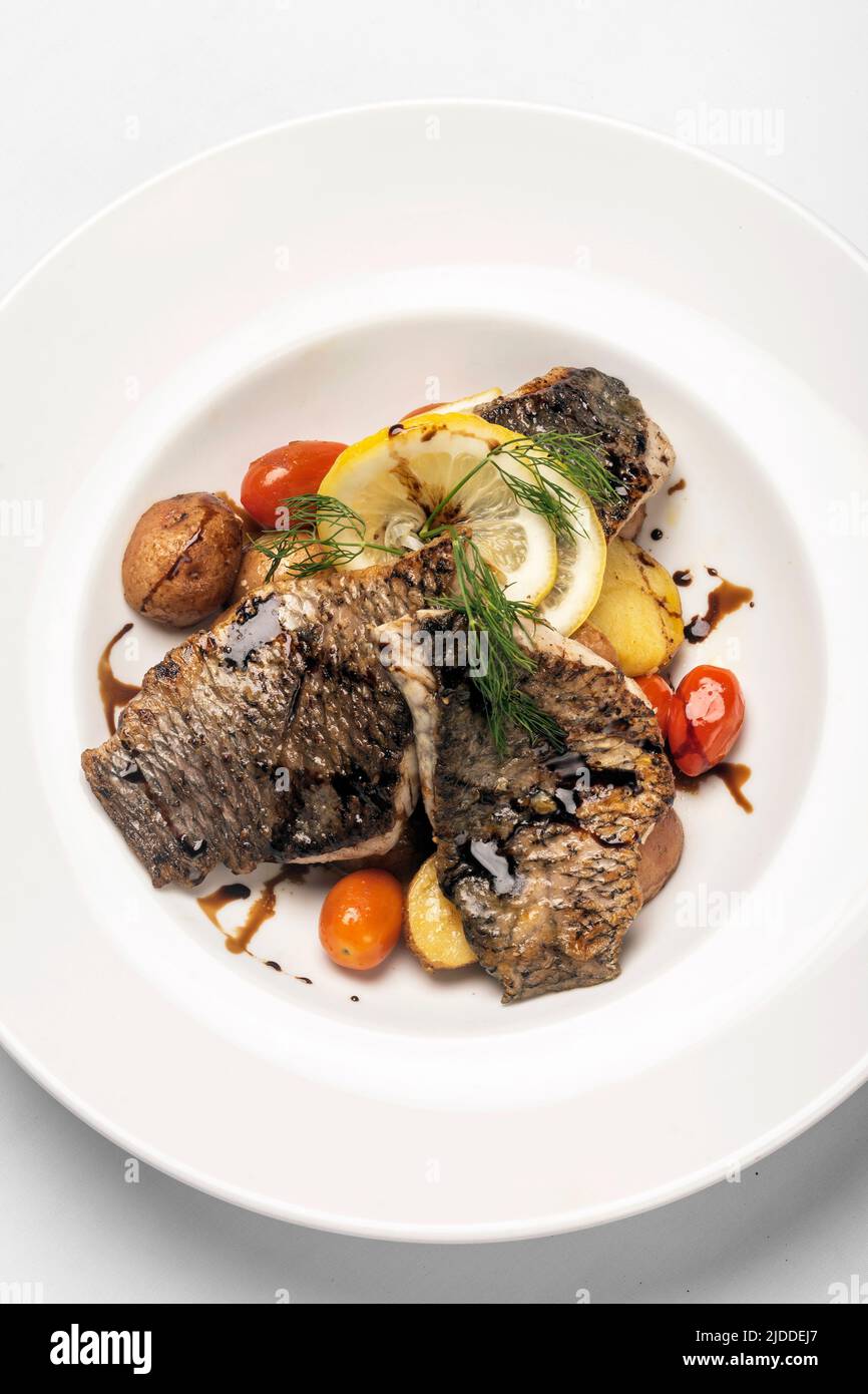 seared fresh sea bass fillet meal with potato and vegetables on white ...