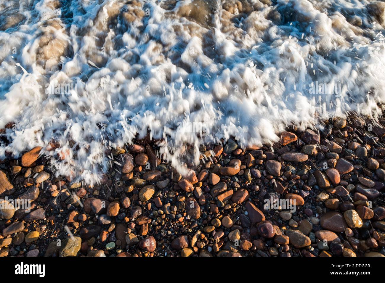 Small red pebbles washed by waves on a beach in Las Flores, Maldonado ...