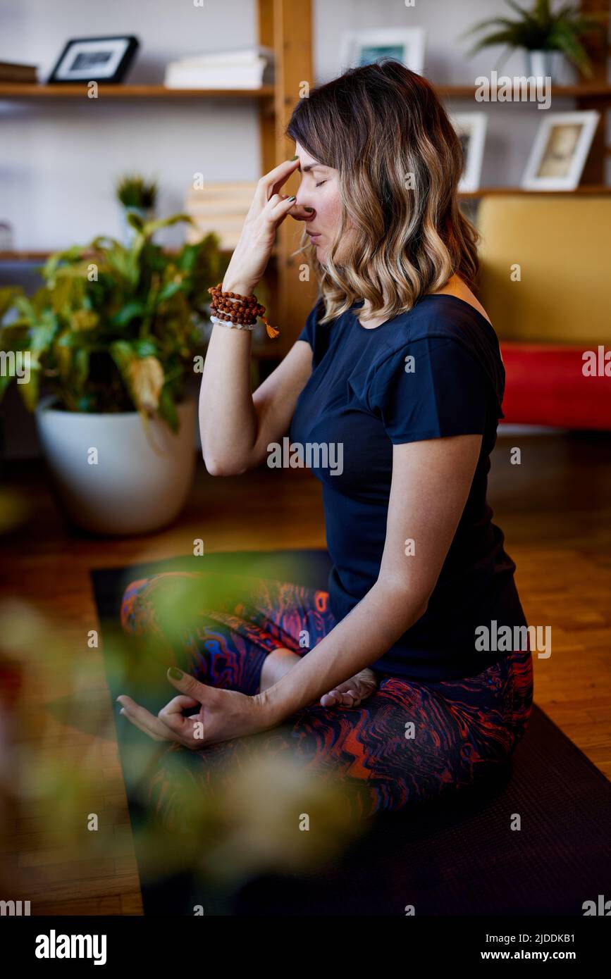 A yogi woman is sitting on a yoga mat in the lotus position and doing ...