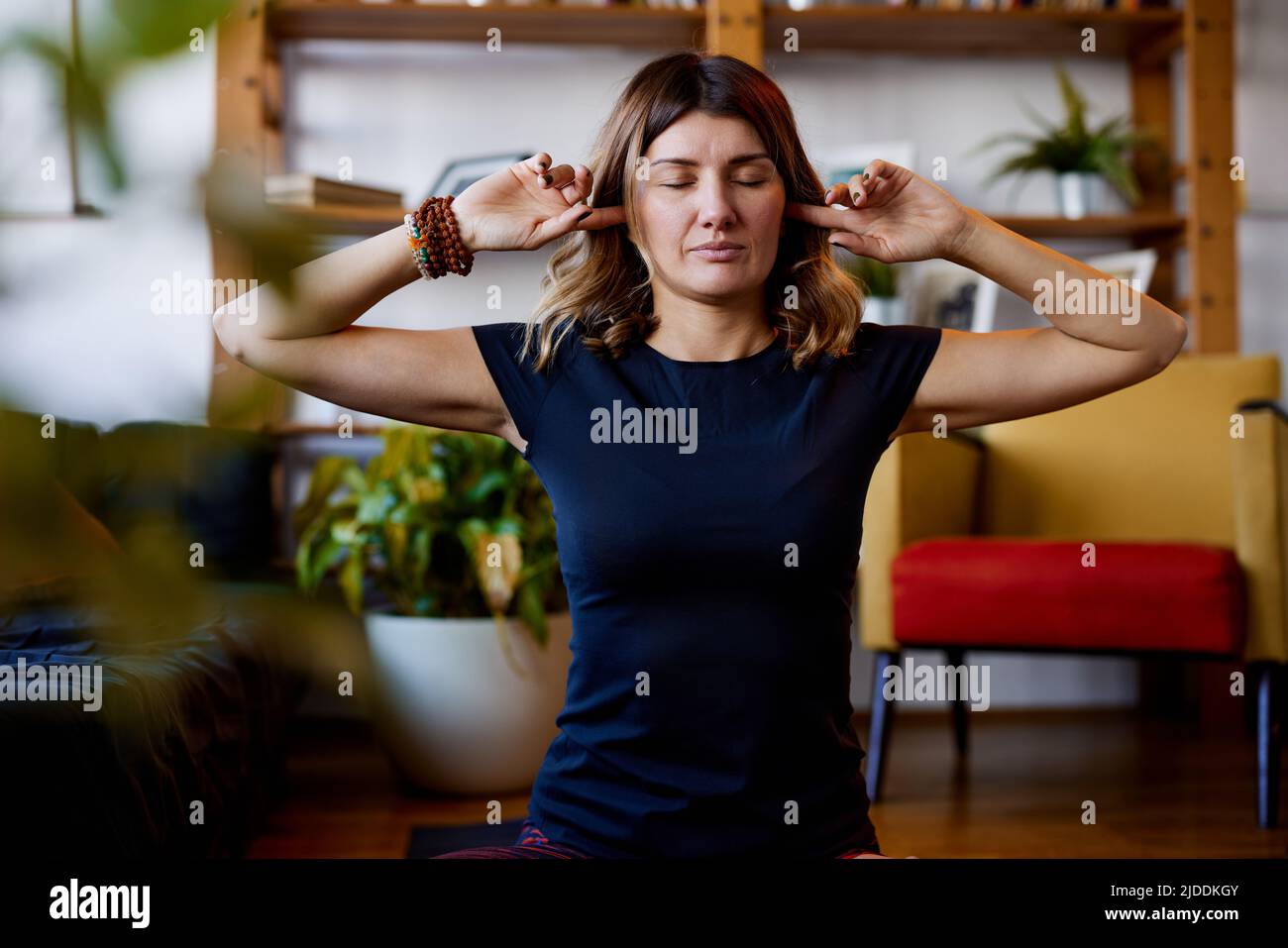 A yogi woman sitting in the lotus yoga pose and practicing bee breath ...
