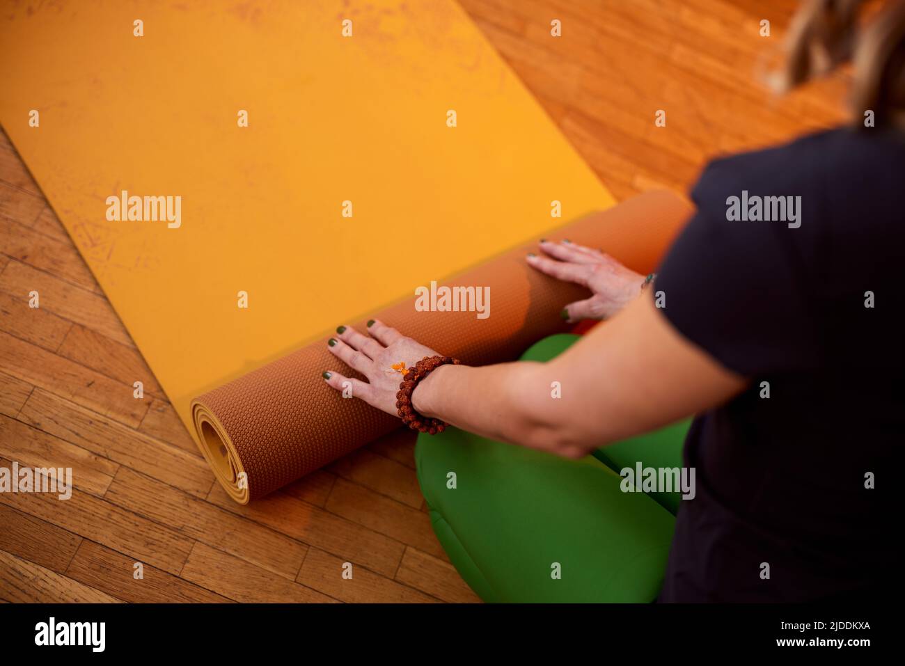 Close up of yogi woman's hands rolling up a yoga mat at home. Hands ...