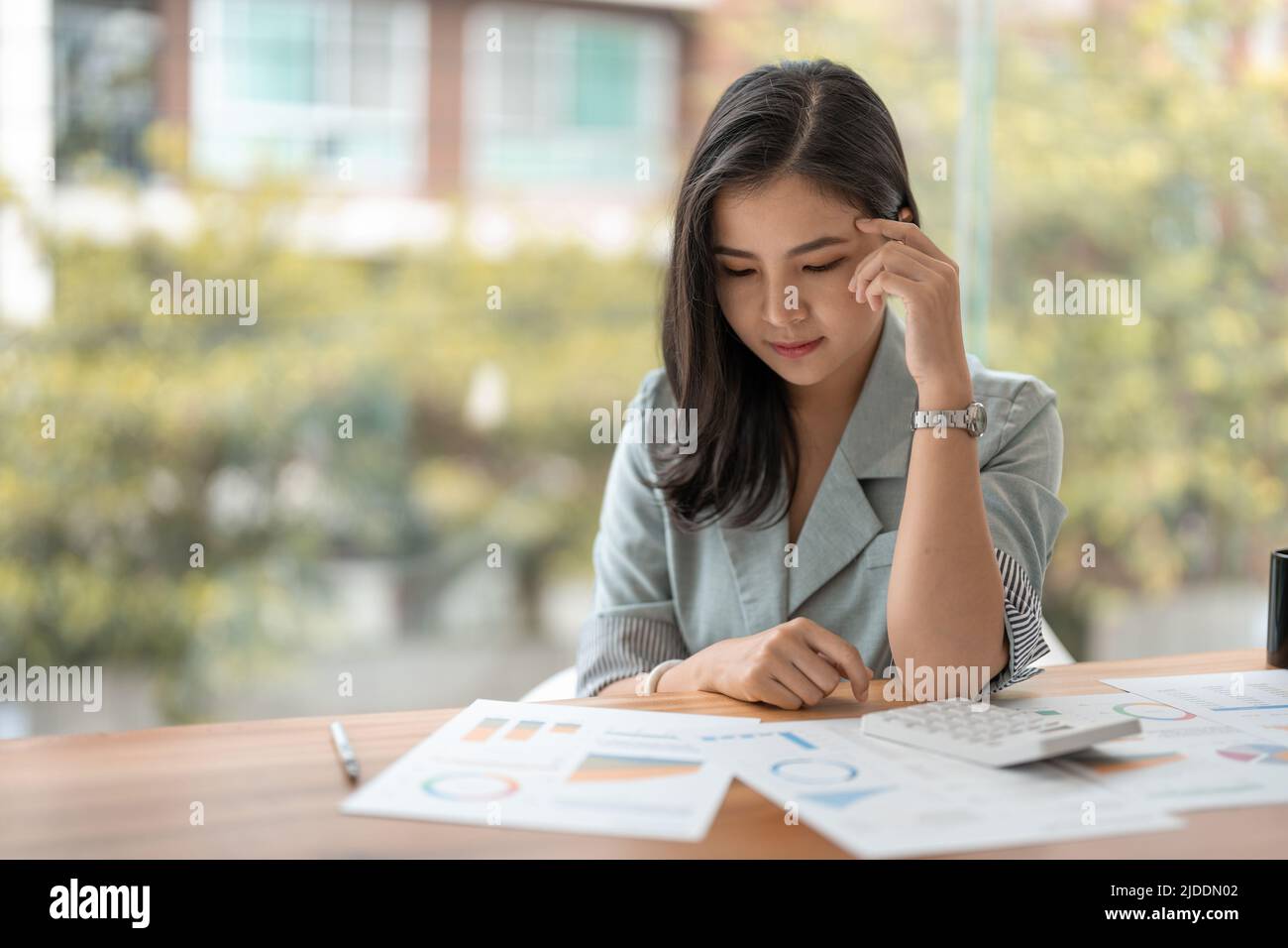 Thoughtful asian woman managing budget and finances using calculator in ...