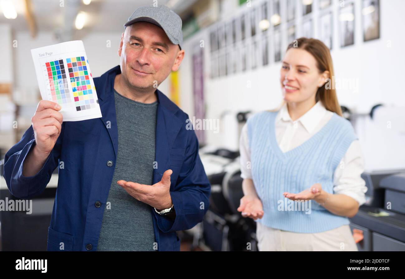 Service engineer and office worker checking color chart test page ...
