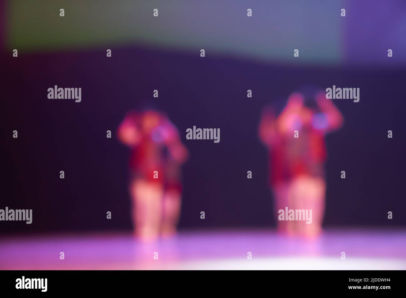 Silhouettes of small dancers in red suits. Colored blurred background ...