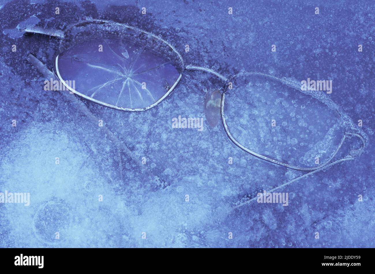 Pair of glasses with smashed lenses and broken arms embedded in ice ...