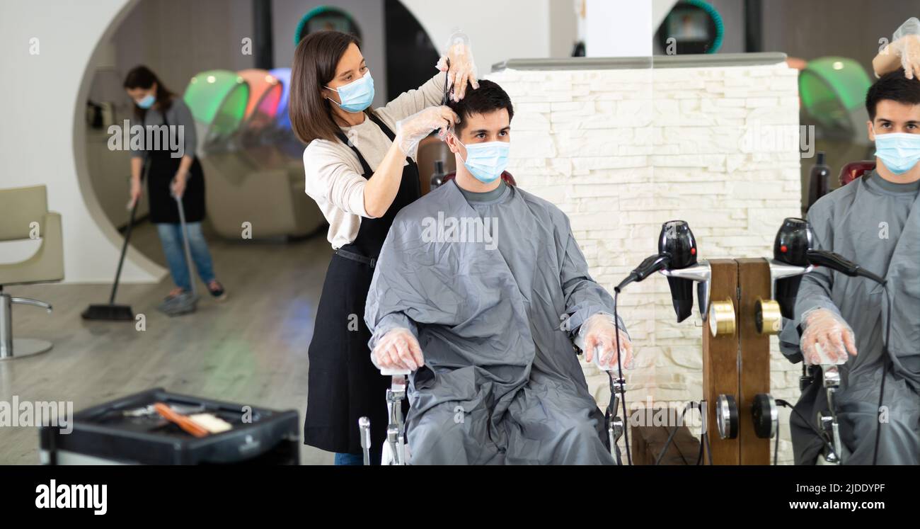 Client in mask during hair cut by professional hairdresser in mask ...