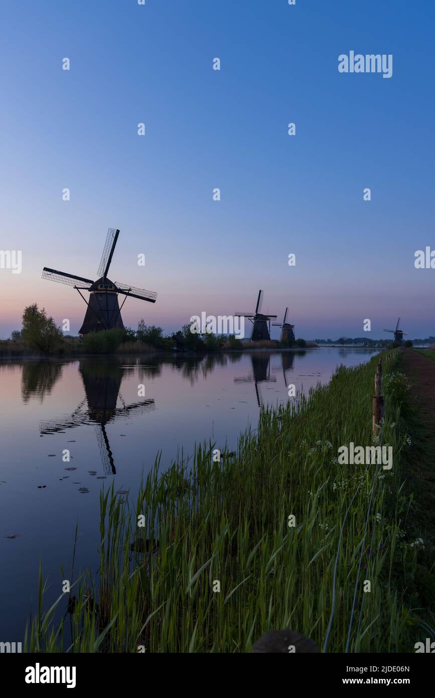 Traditional Dutch windmills with a colourful sky just before sunrise in ...