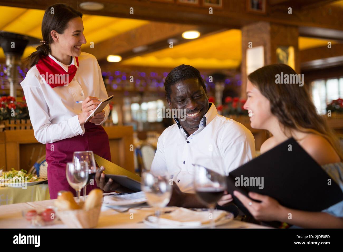 Positive young couple making order at restaurant Stock Photo - Alamy