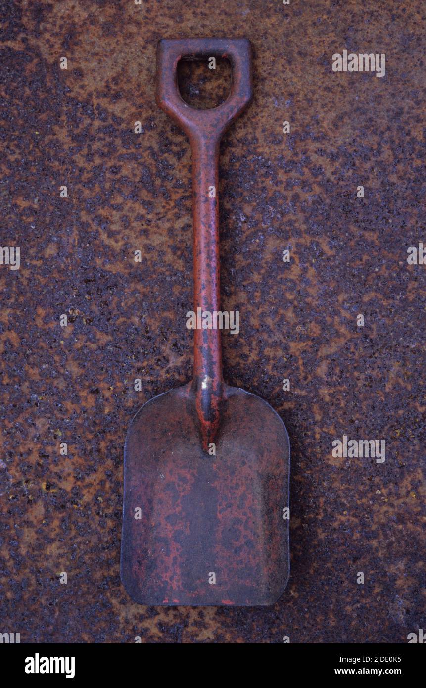 Worn and scratched red painted metal hand spade for use on beach or in ...