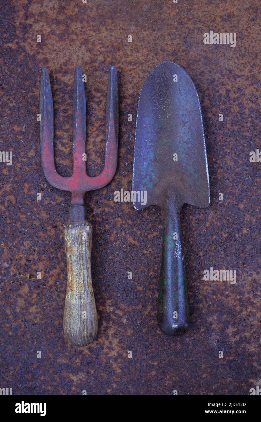 Well-used garden trowel and hand fork lying on rusty metal sheet Stock ...