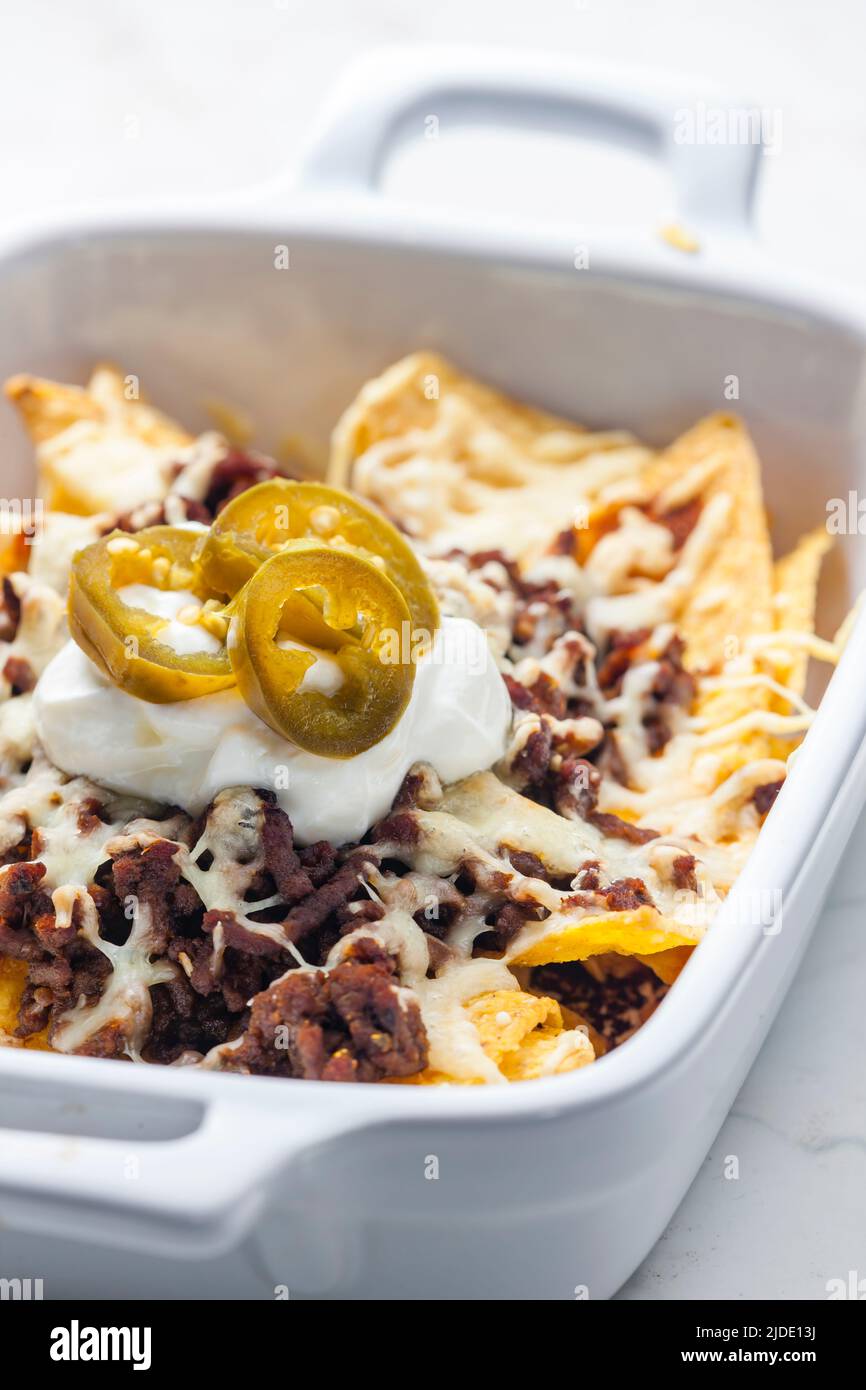 nachos with beef minced meat and cheese served with whipped cream and ...
