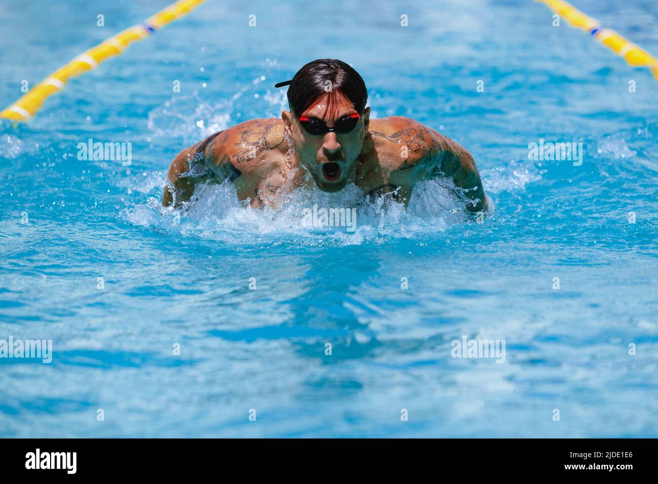 Young muscular man, professional swimmer in goggles training at public ...