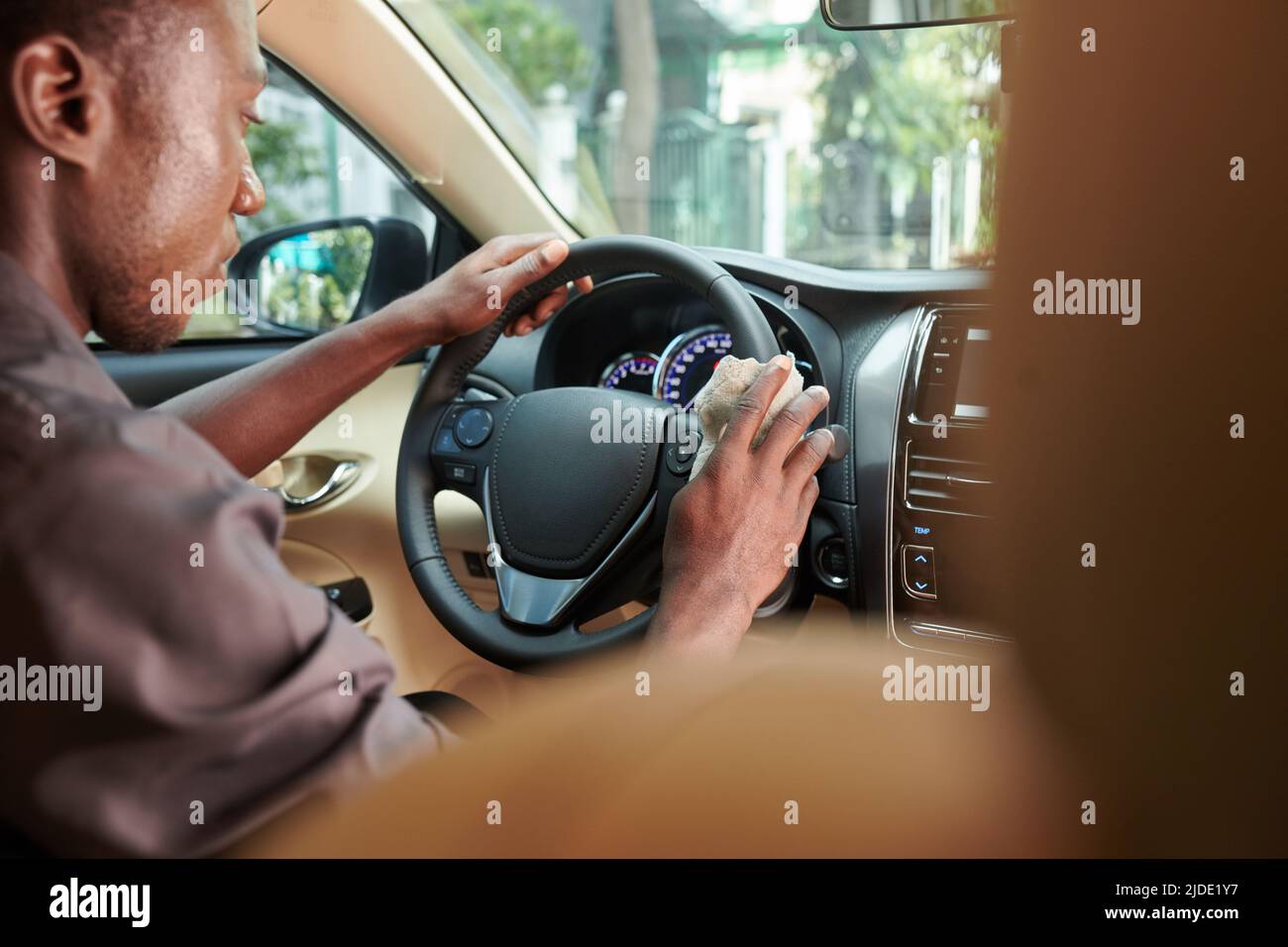 Taxi driver cleaning steering wheel with wet cloth to wipe off dust ...