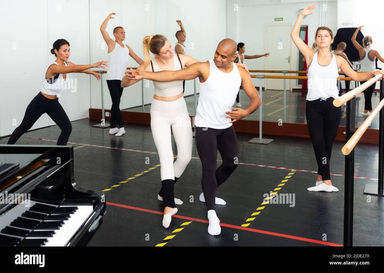 female ballet teacher showing moves in front of a group of multiracial ...