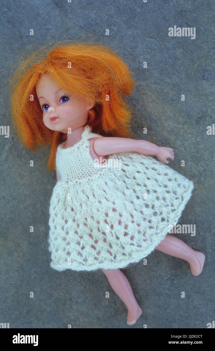 Modern girl doll with white knitted dress and ginger hair lying on her ...