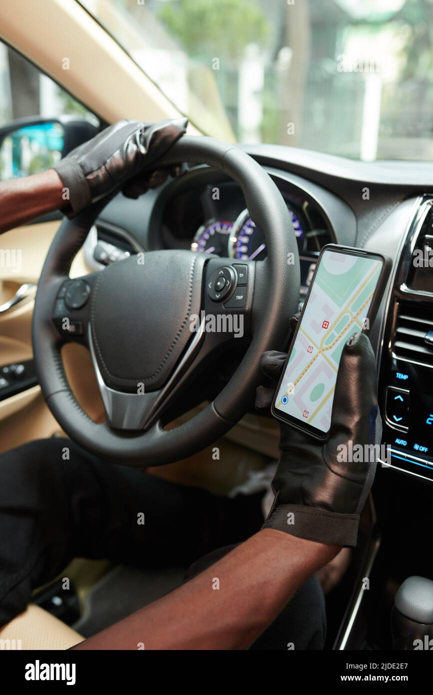 Close-up image of driver checking map application on smartphone when ...