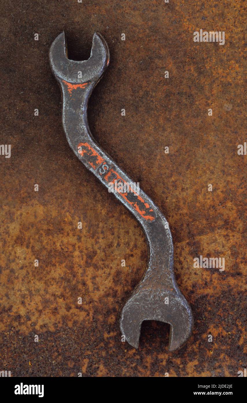 Heavy double-headed spanner with bend in handle lying on rusty metal ...