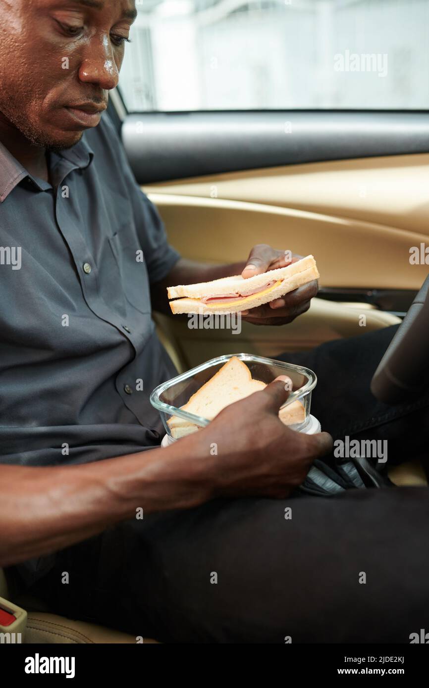 Taxi driver eating ham and cheese sandwich for lunch when sitting in ...