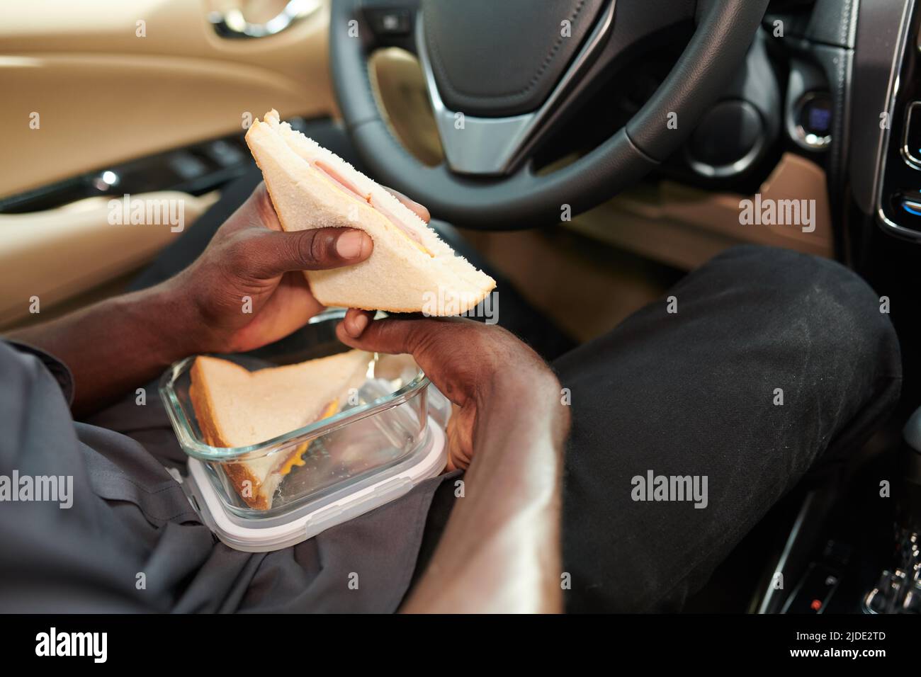 Hands of taxi driver eating tasty homemade sandwich he made at home for ...