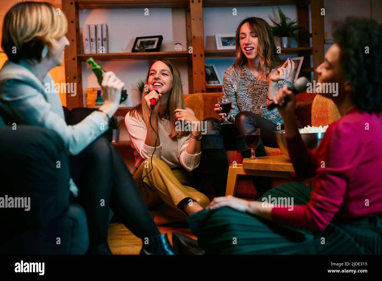 Happy multicultural friends sitting at home, laughing, singing, and ...