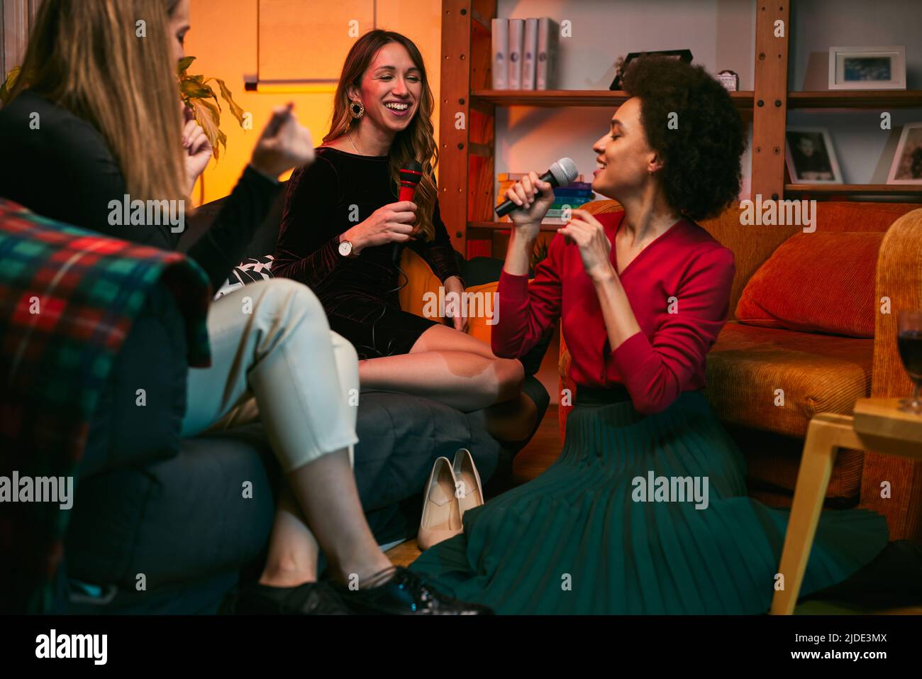 A multicultural group of female friends sings karaoke while drinking ...
