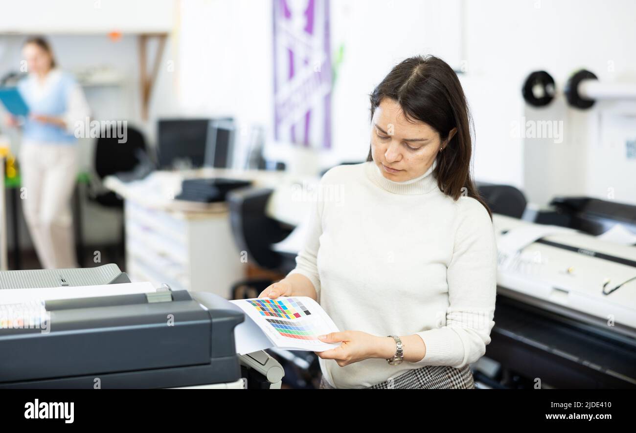 Female employee of the copy center checks the quality of the print on ...
