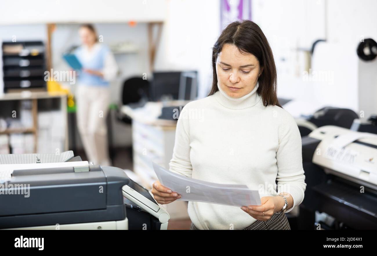 Portrait of an attentive woman checking the quality of printing in ...