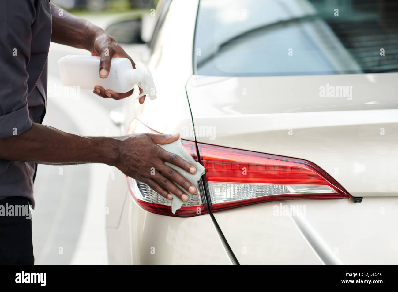 Closeup image of car owner cleaning dirty back lights with dissolved ...