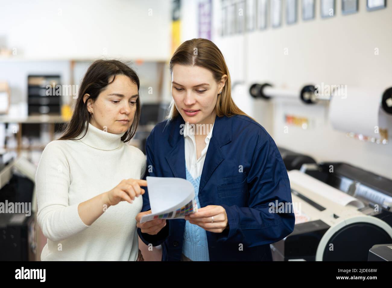 Two employees of printing house are discussing quality of plotter ...