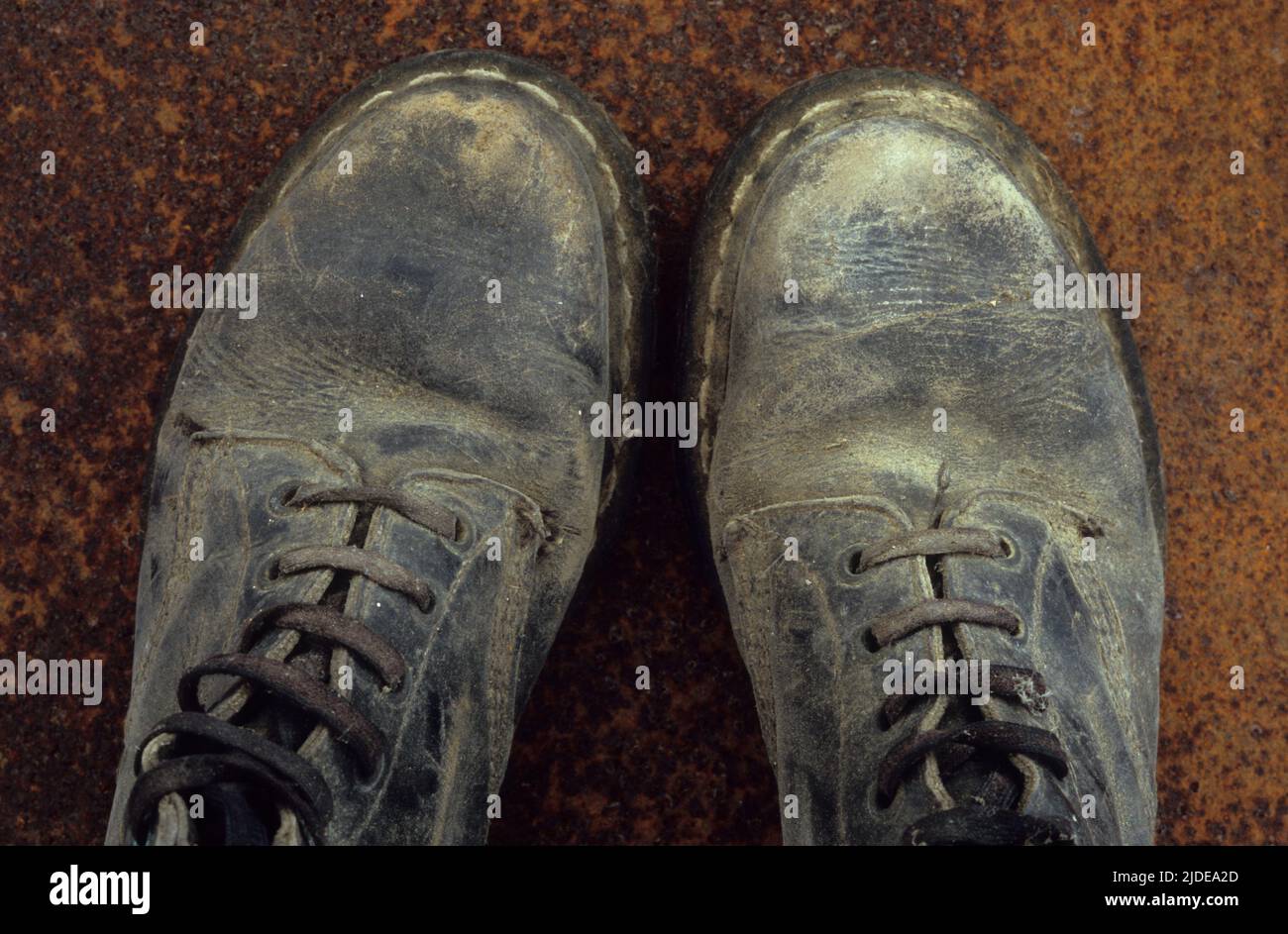 Pair of well-worn black heavy-duty industrial working boots standing on ...