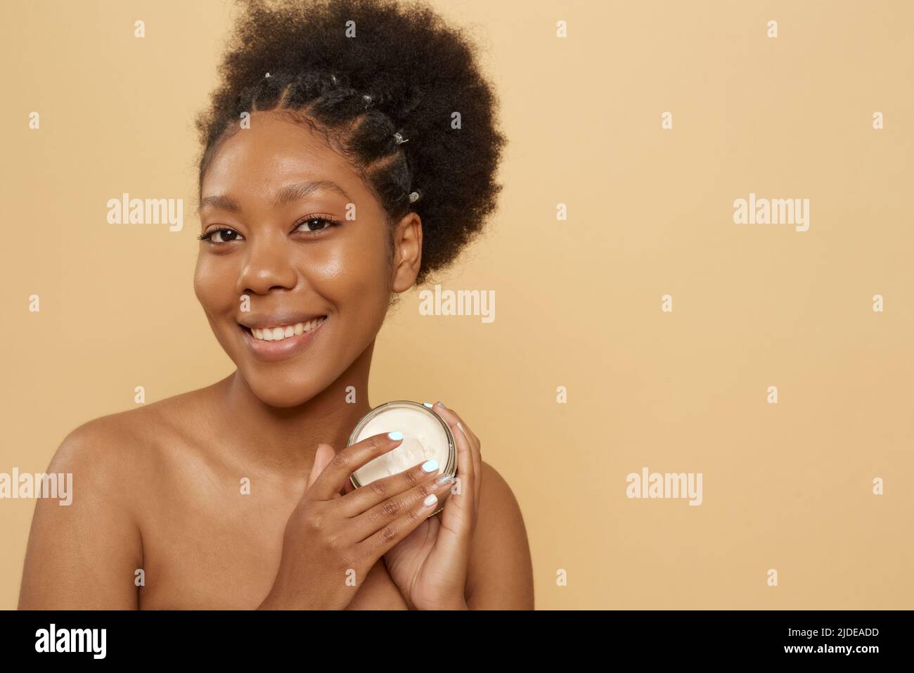 Beautiful african american woman holding jar of moisturizer or mask on ...